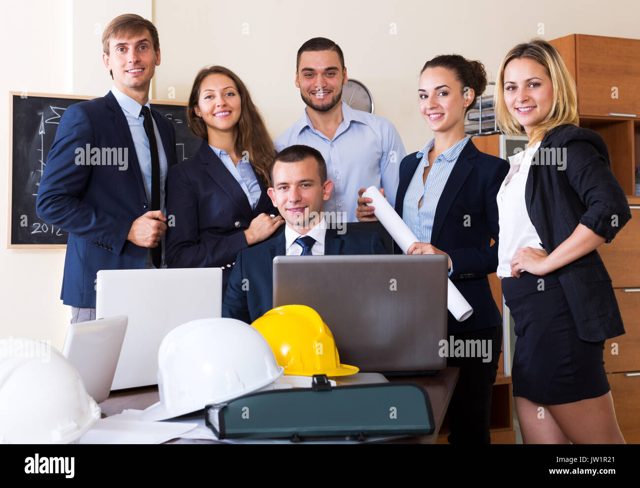 Team of architectural engineers with laptops and blueprints in office ...