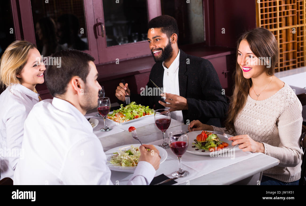 Group of friends eating at restaurant table and chatting Stock Photo ...