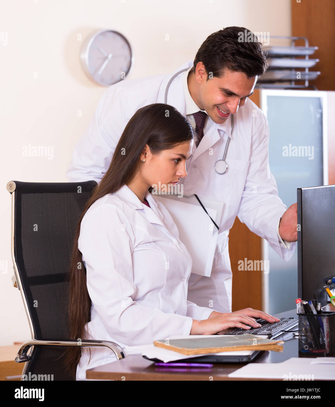 Young intern asking advice from doctor at clinic reception Stock Photo ...