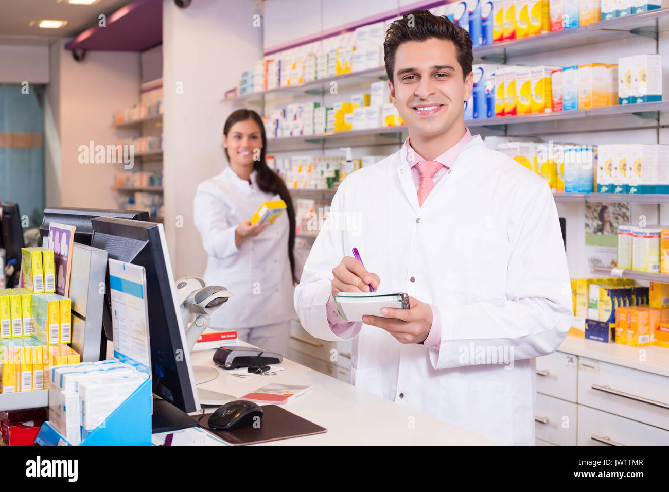 Portrait of happy pharmacist and assistant working at farmacy reception ...