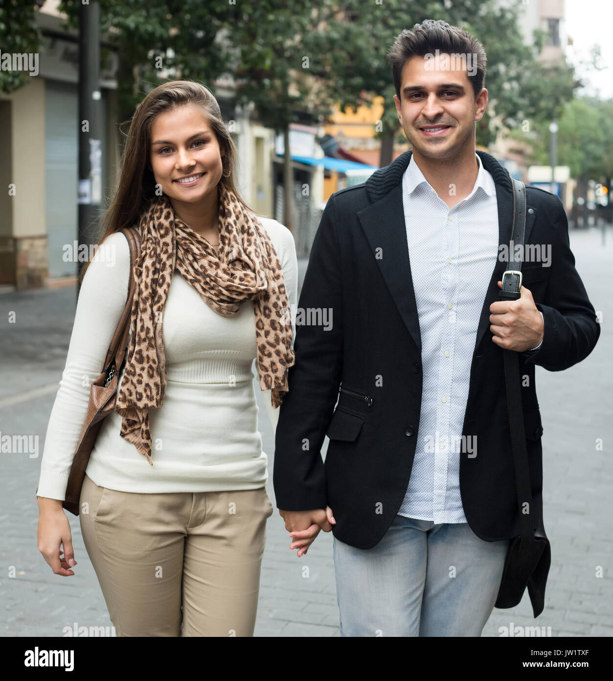 Smiling handsome man having date with attractive girlfriend outdoors ...