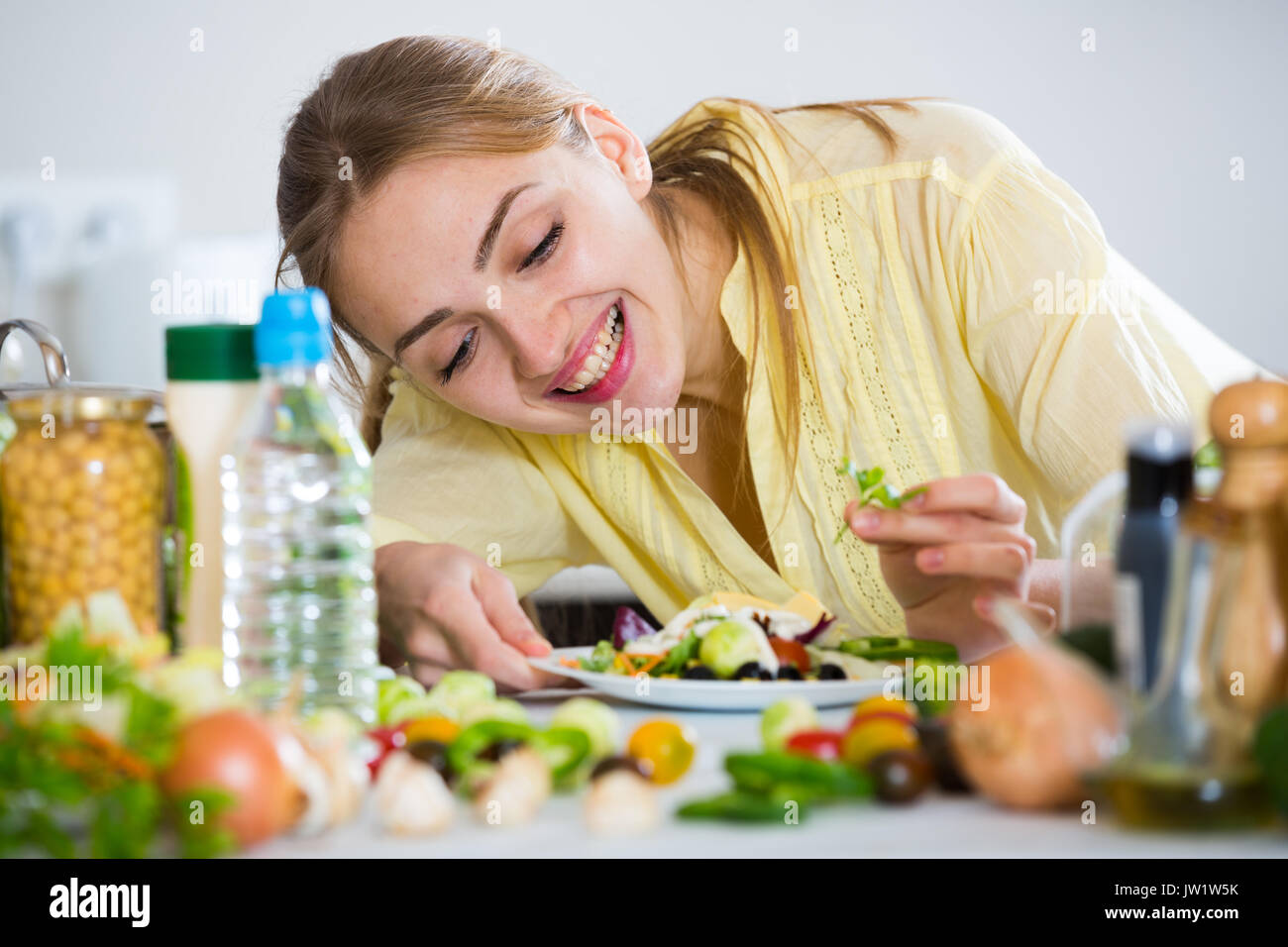 Positive girl with long hair cooking salad at home Stock Photo - Alamy