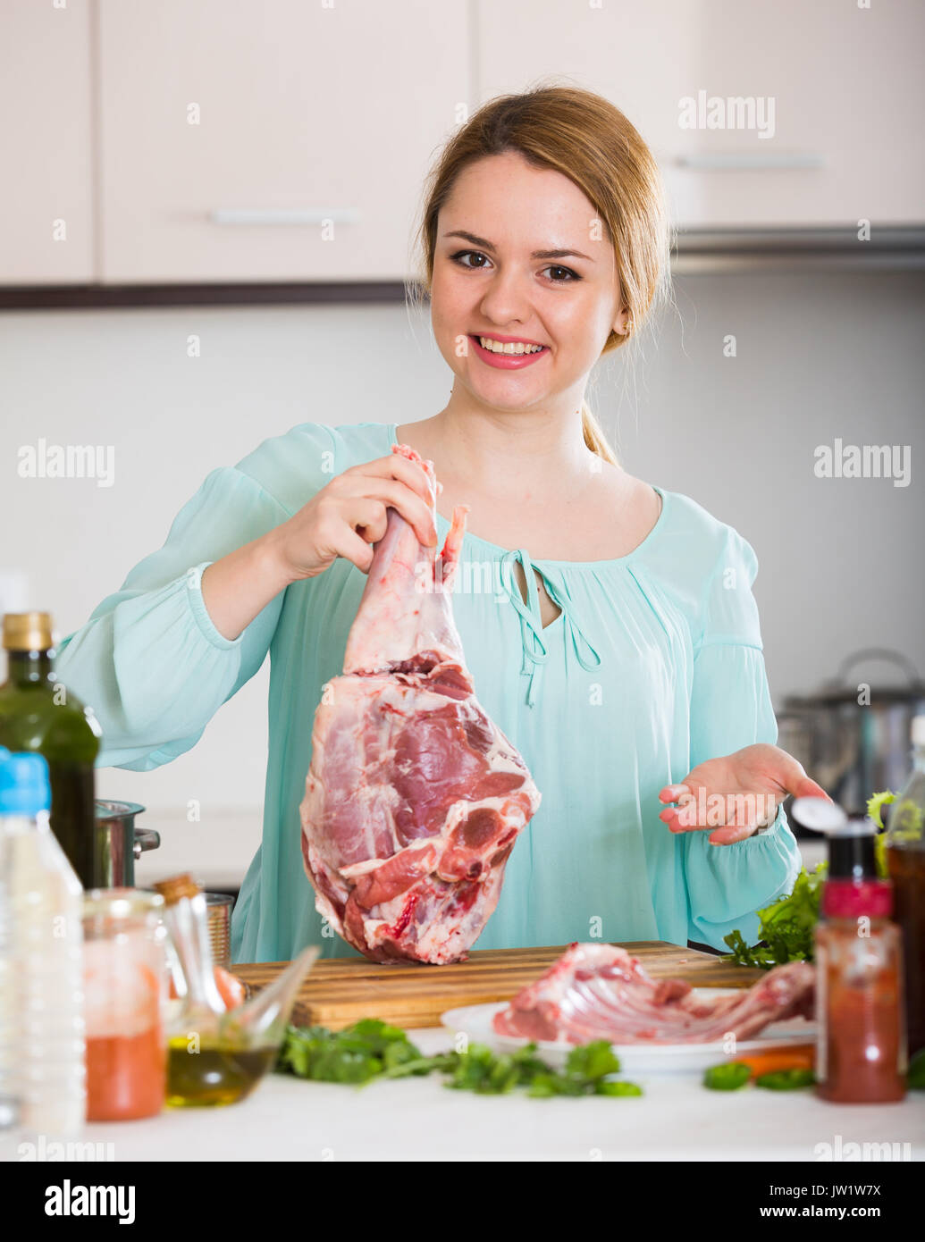 Smiling long-haired brunette girl with lamb ribs and hock Stock Photo ...