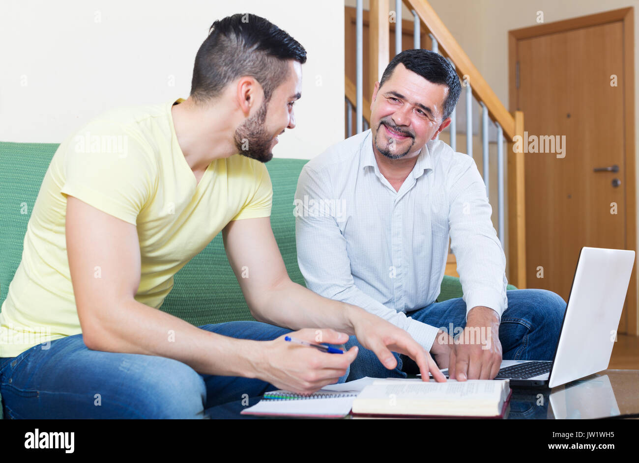 Positive professor giving private lesson to young student at home Stock ...