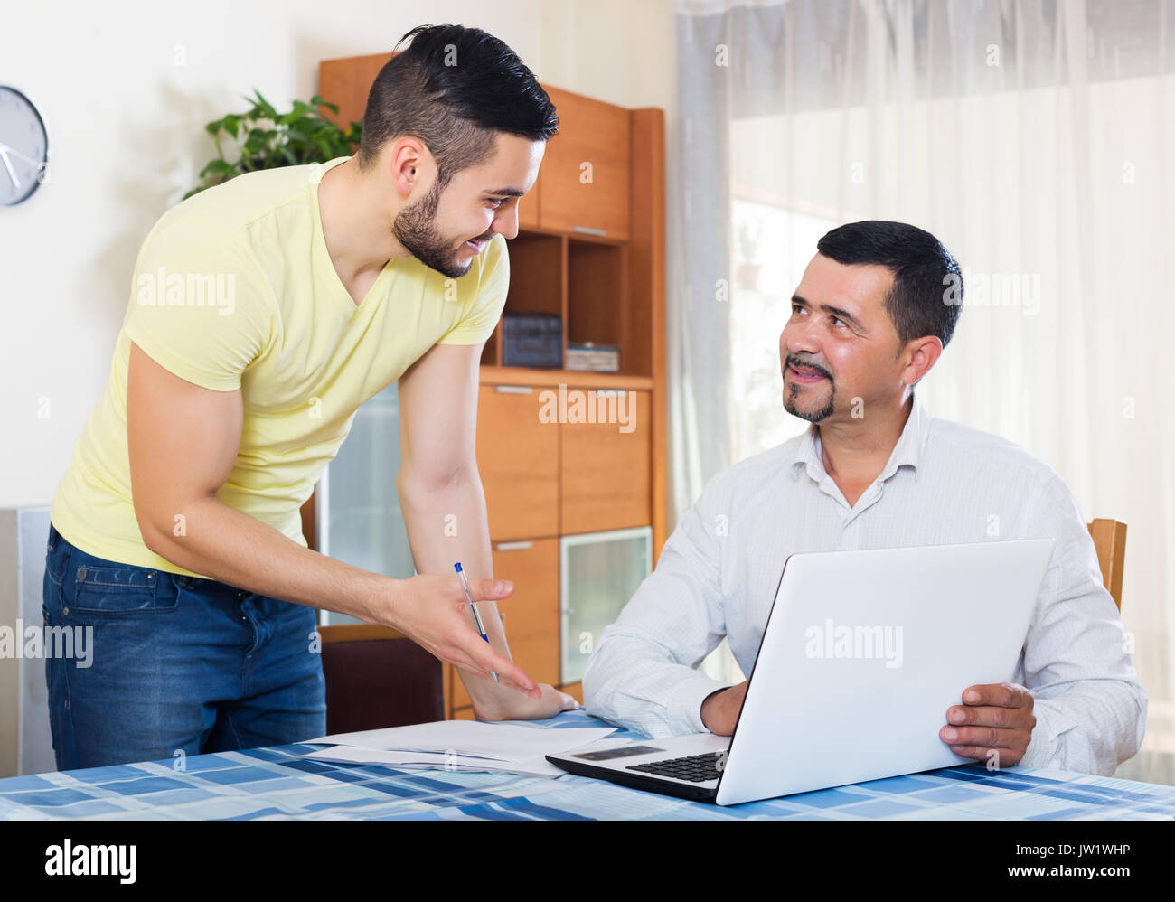 Mature father helping smiling adult son to fill application form Stock ...
