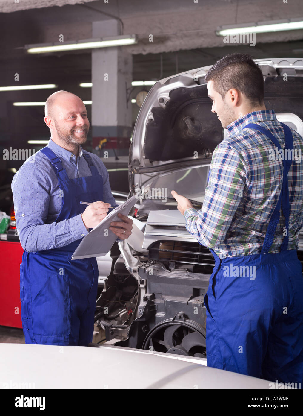 Workman calculating the cost of work at auto repair shop Stock Photo ...