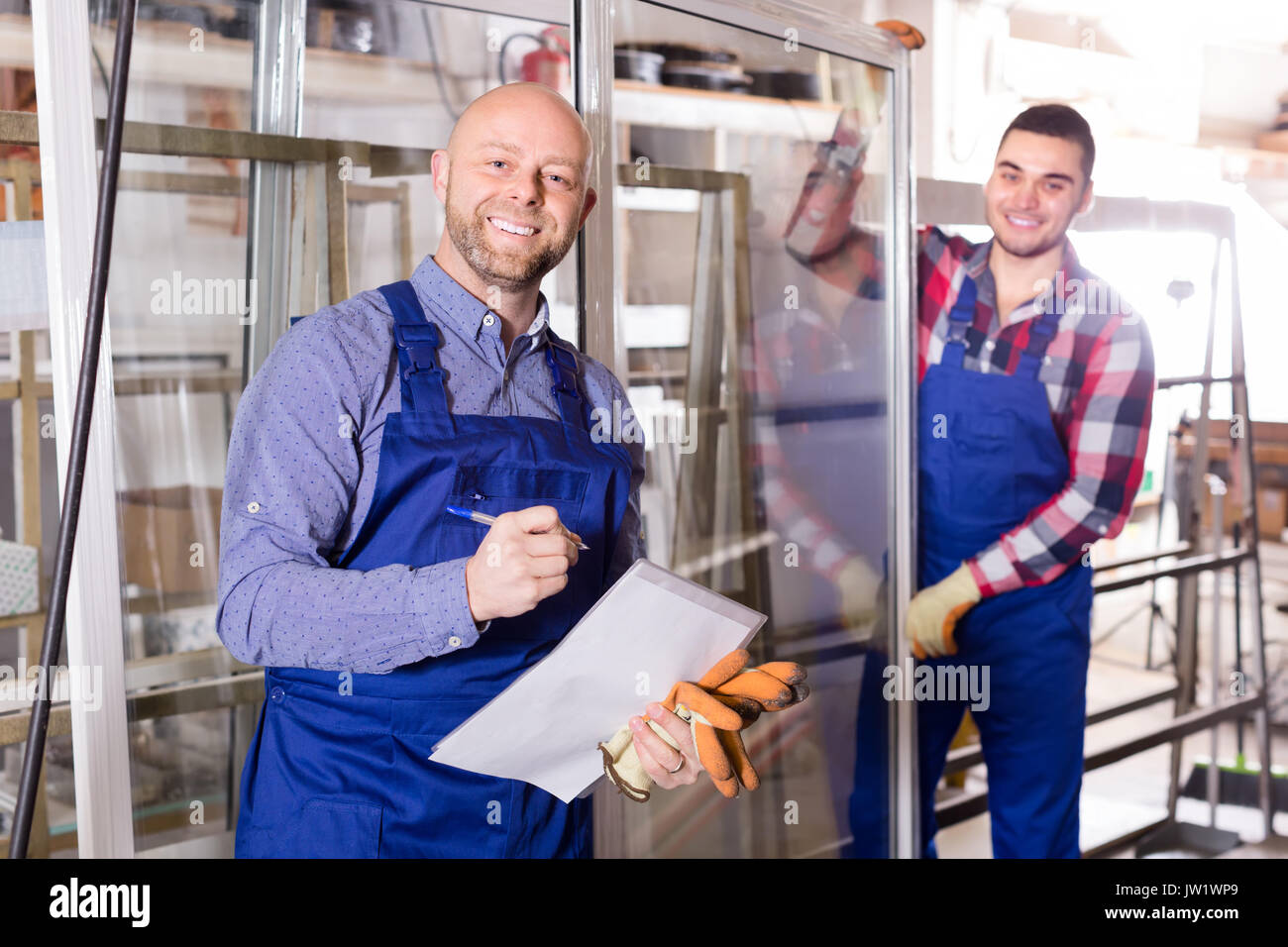 Two happy smiling workers near PVC window frames at factory Stock Photo ...