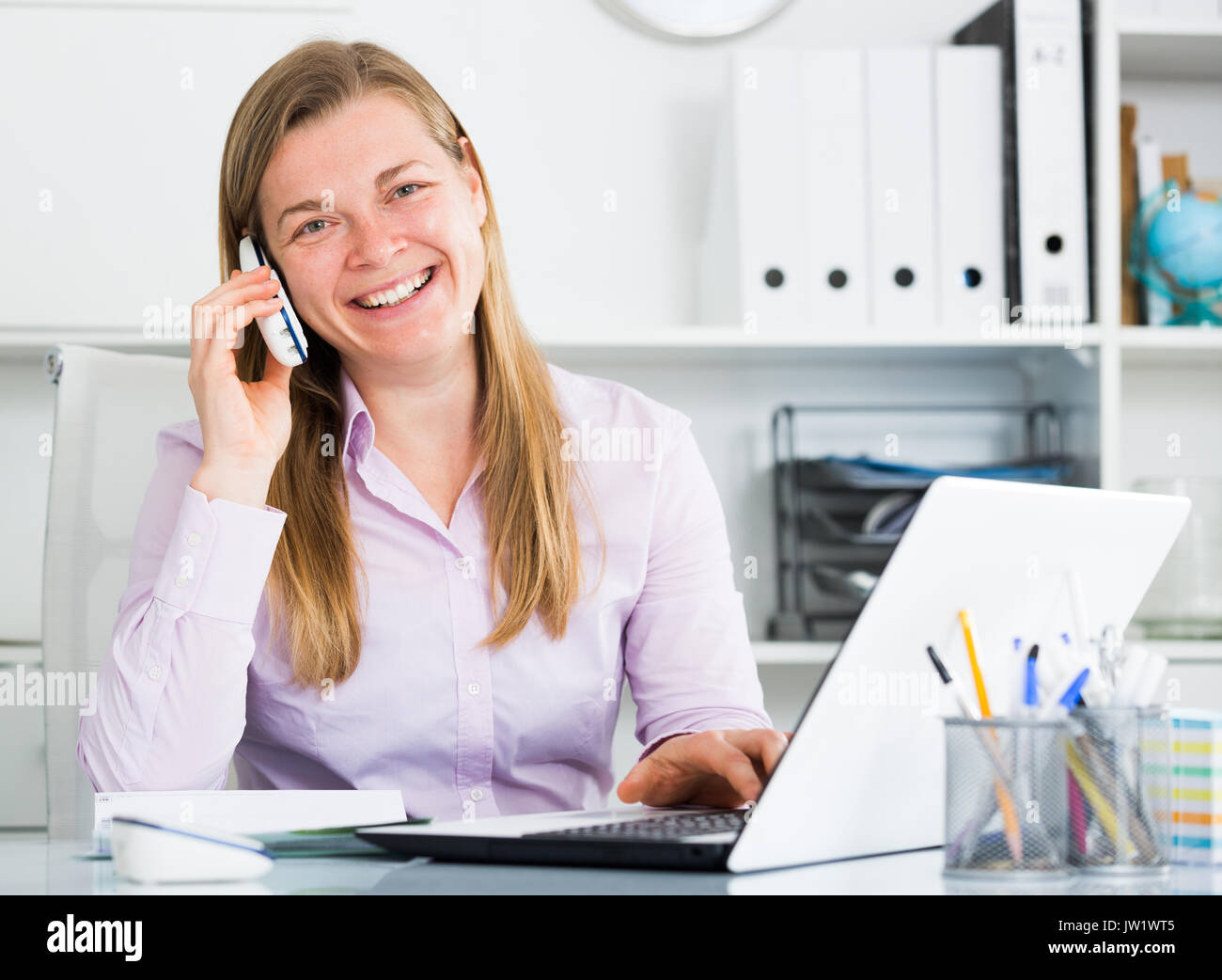 Female employee having conversation on phone during work Stock Photo ...