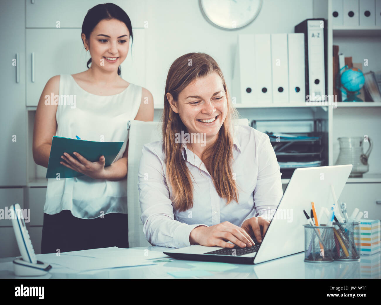 Female senior manager examining work of woman newcomer in office Stock ...