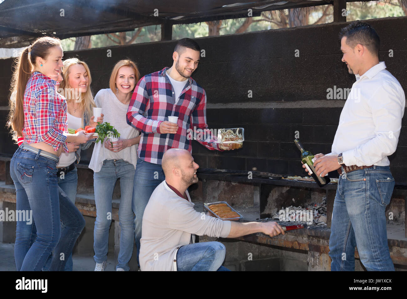 Positive colleagues making grill at corporate party outdoor. Selective ...