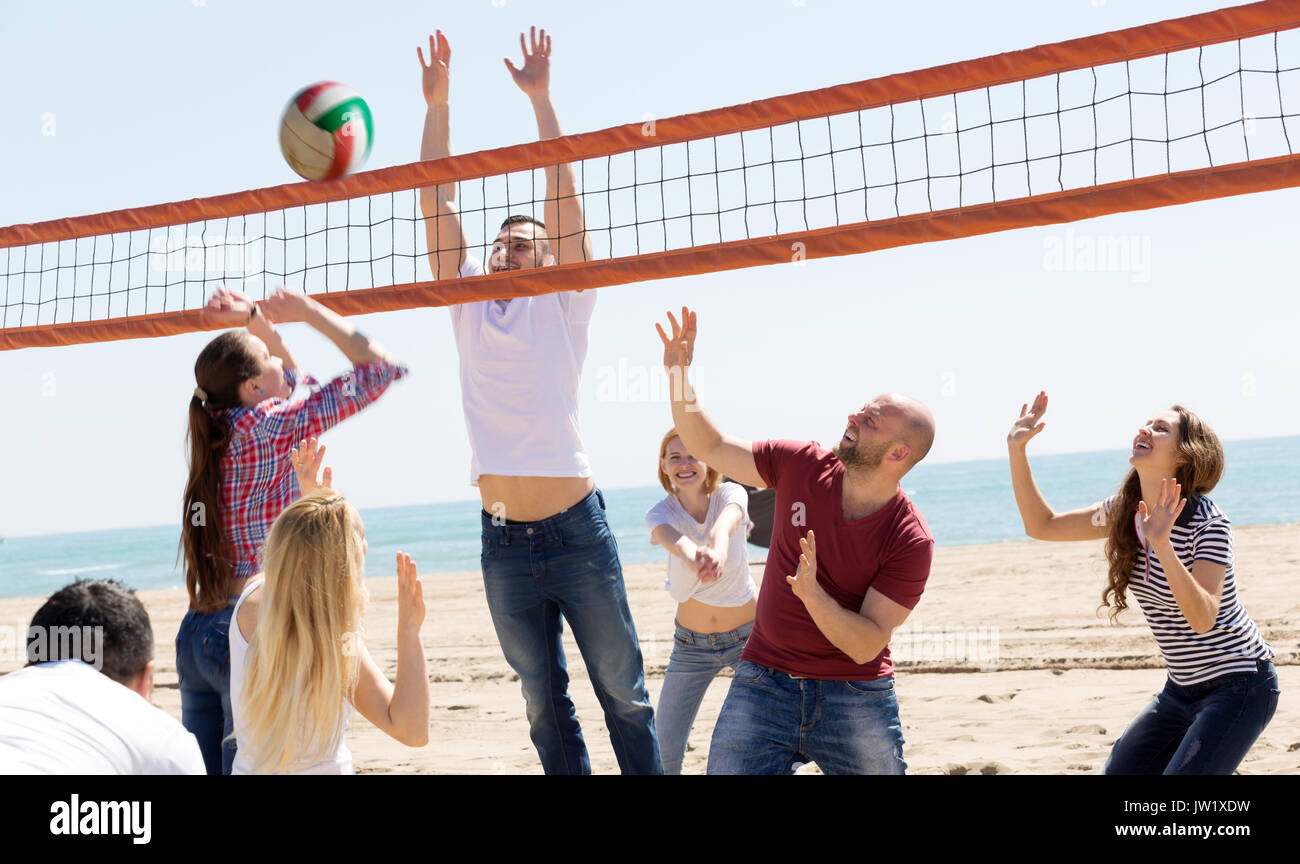 Cheerful adults throwing ball over net and laughing. Focus on the right ...