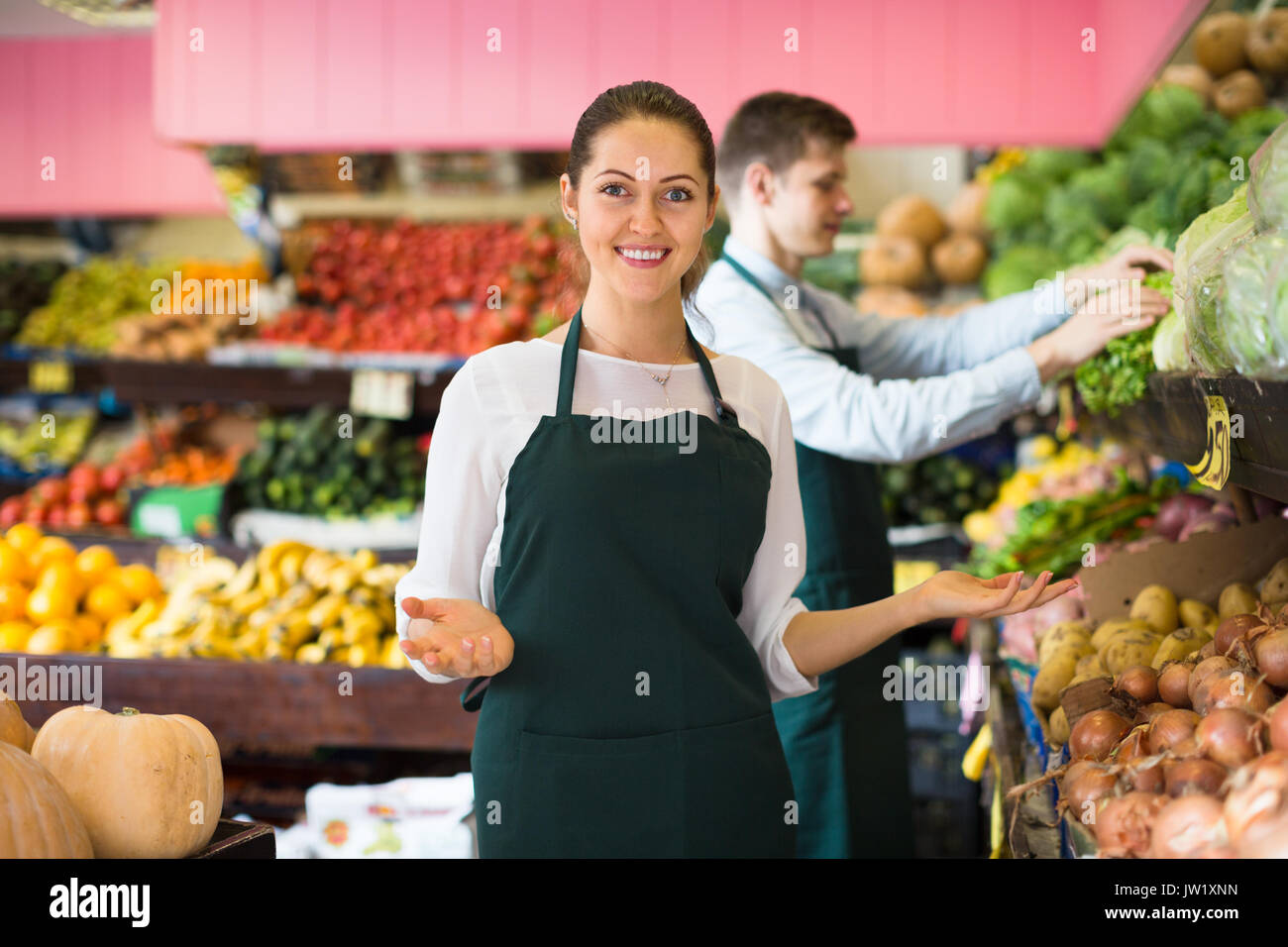 Young friendly workers selling fresh fruits and vegetables on market ...