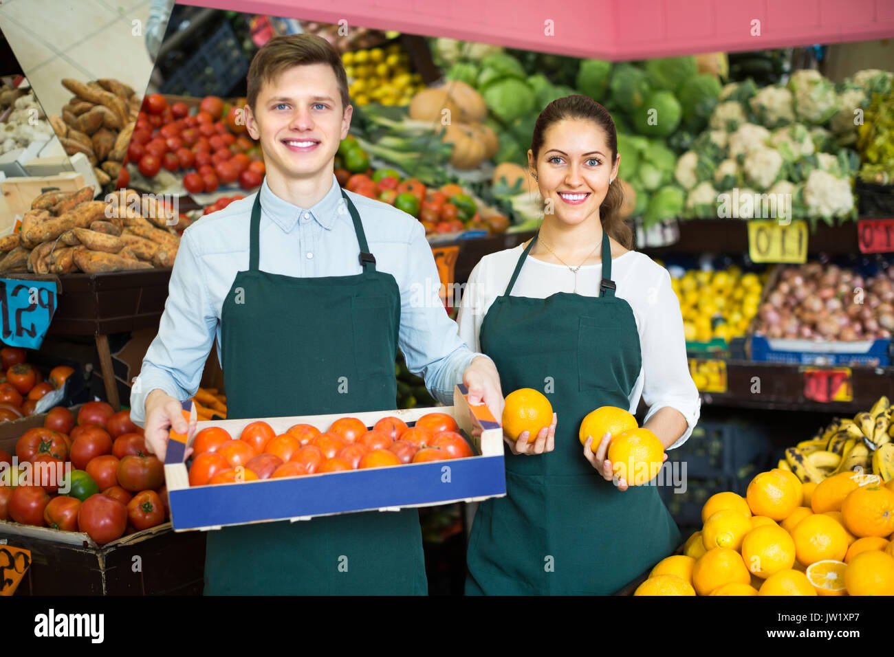 Positive supermarket workers working in fruit and vegetables section ...