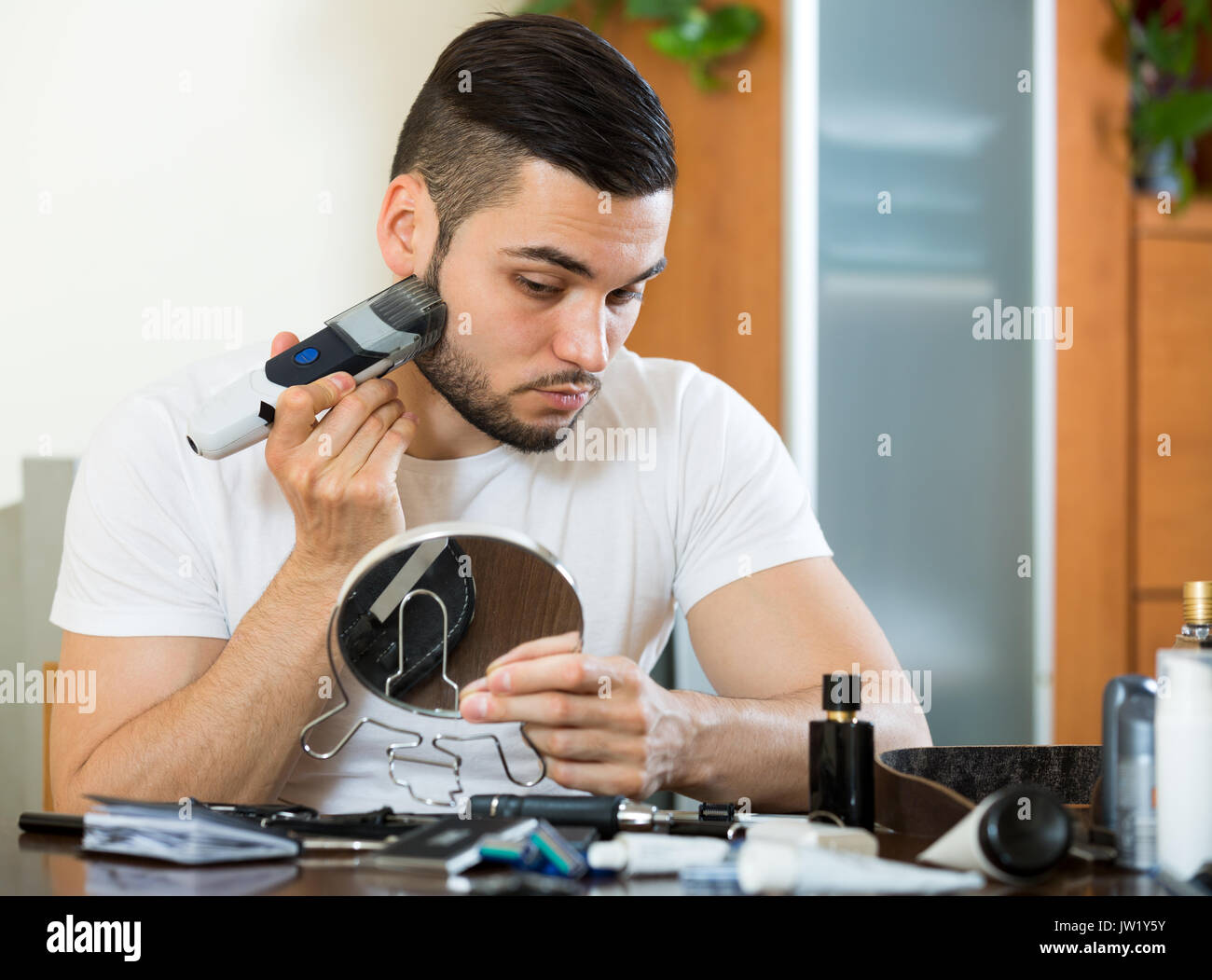 Handsome man shaving face with electric razor Stock Photo - Alamy