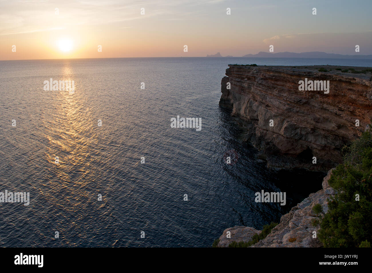 Sunset view of Es Vedrá and Ibiza coastline from Punta Rasa cliffs at ...