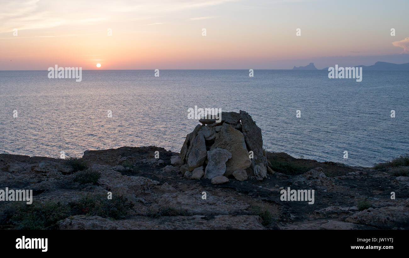 Sunset view of Es Vedrá and Ibiza coastline from Punta Rasa cliffs at ...