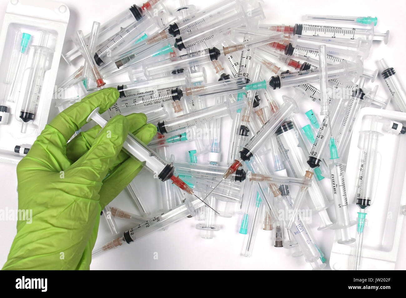 Used medical syringes pile with hand holding injection Stock Photo - Alamy