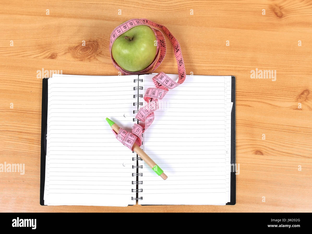 Open notebook with apple and tape measure around pen Stock Photo - Alamy