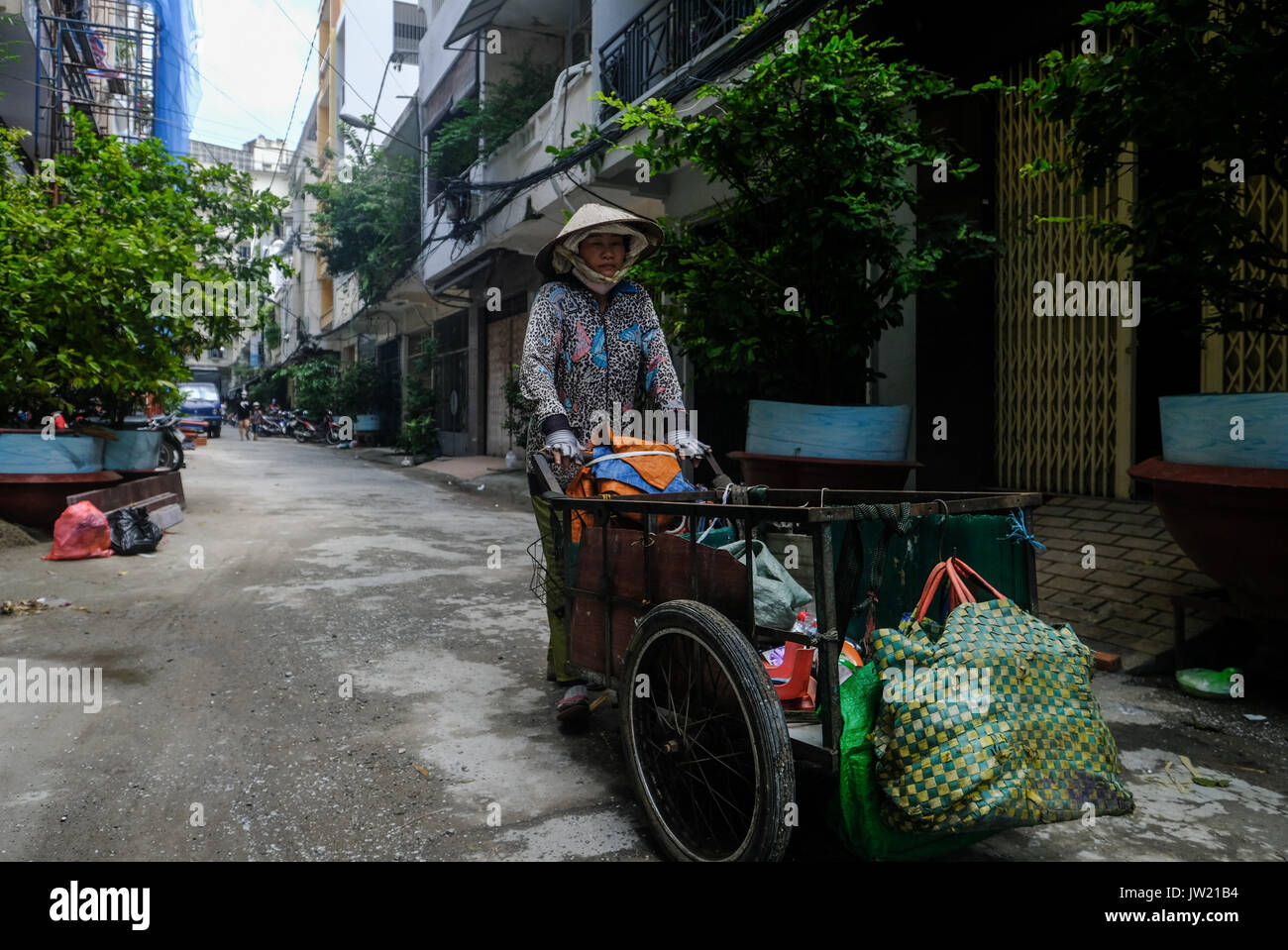 A female Vietnamese street vendor pushes a cart along a street in Ho ...