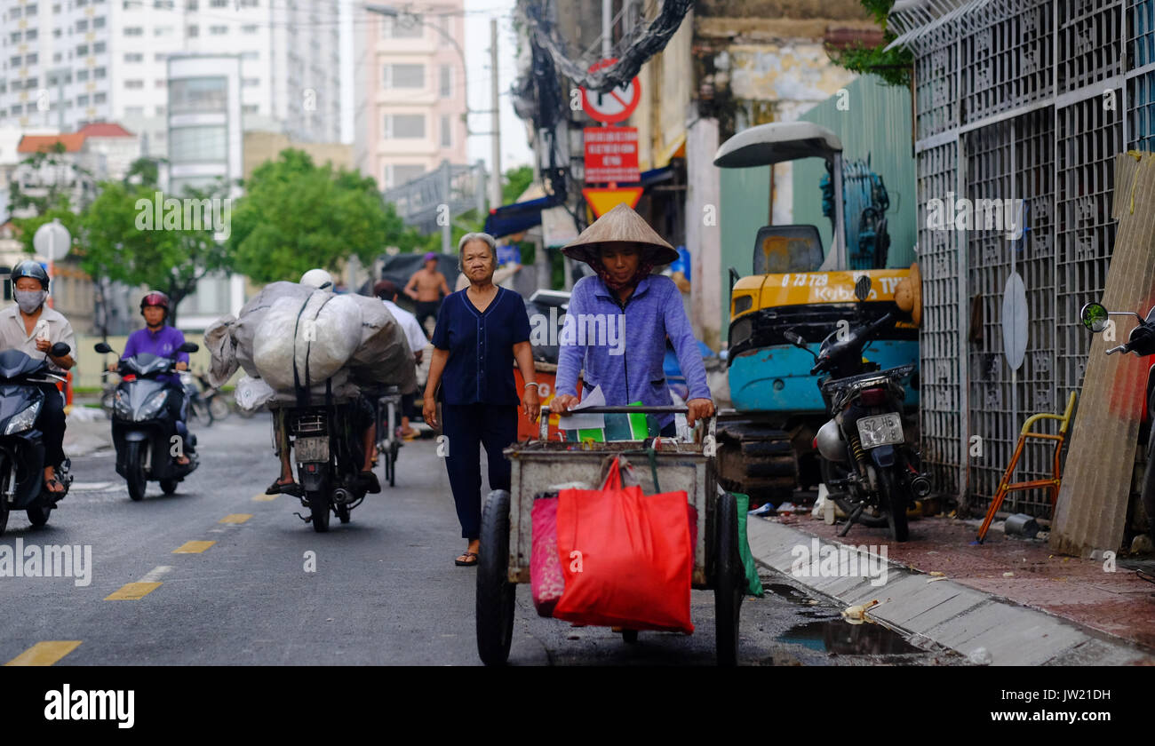 A female Vietnamese street vendor pushes a cart along a street in Ho ...