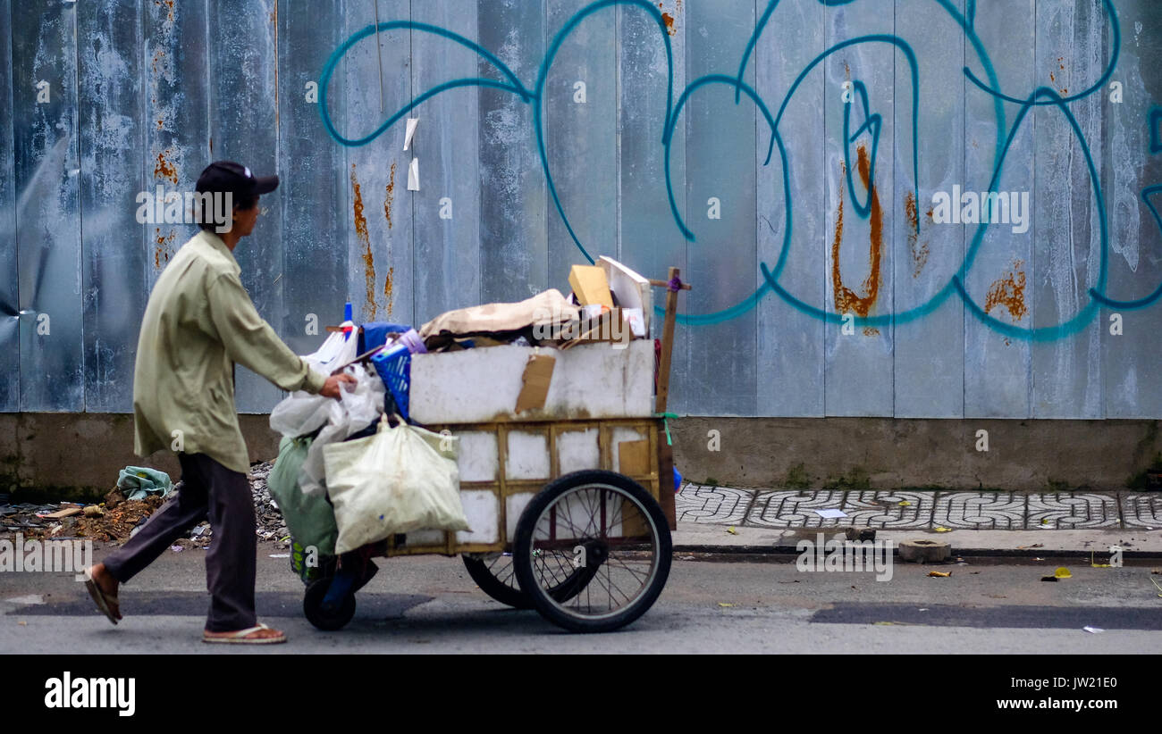 A Vietnamese male pushes a cart along a street in Ho Chi Minh City ...