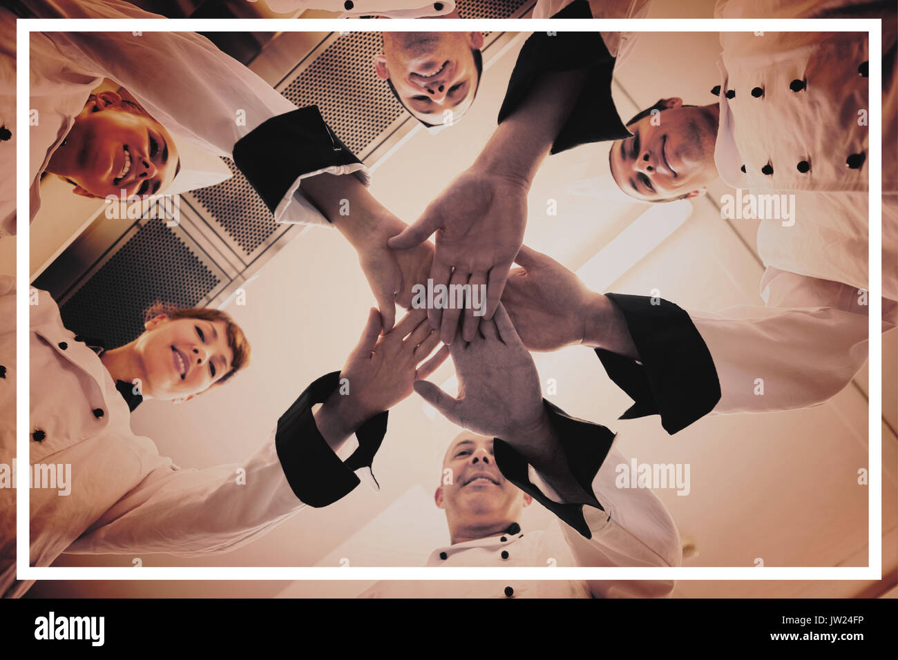 Chefs joining hands in a circle wearing uniforms in a kitchen Stock ...