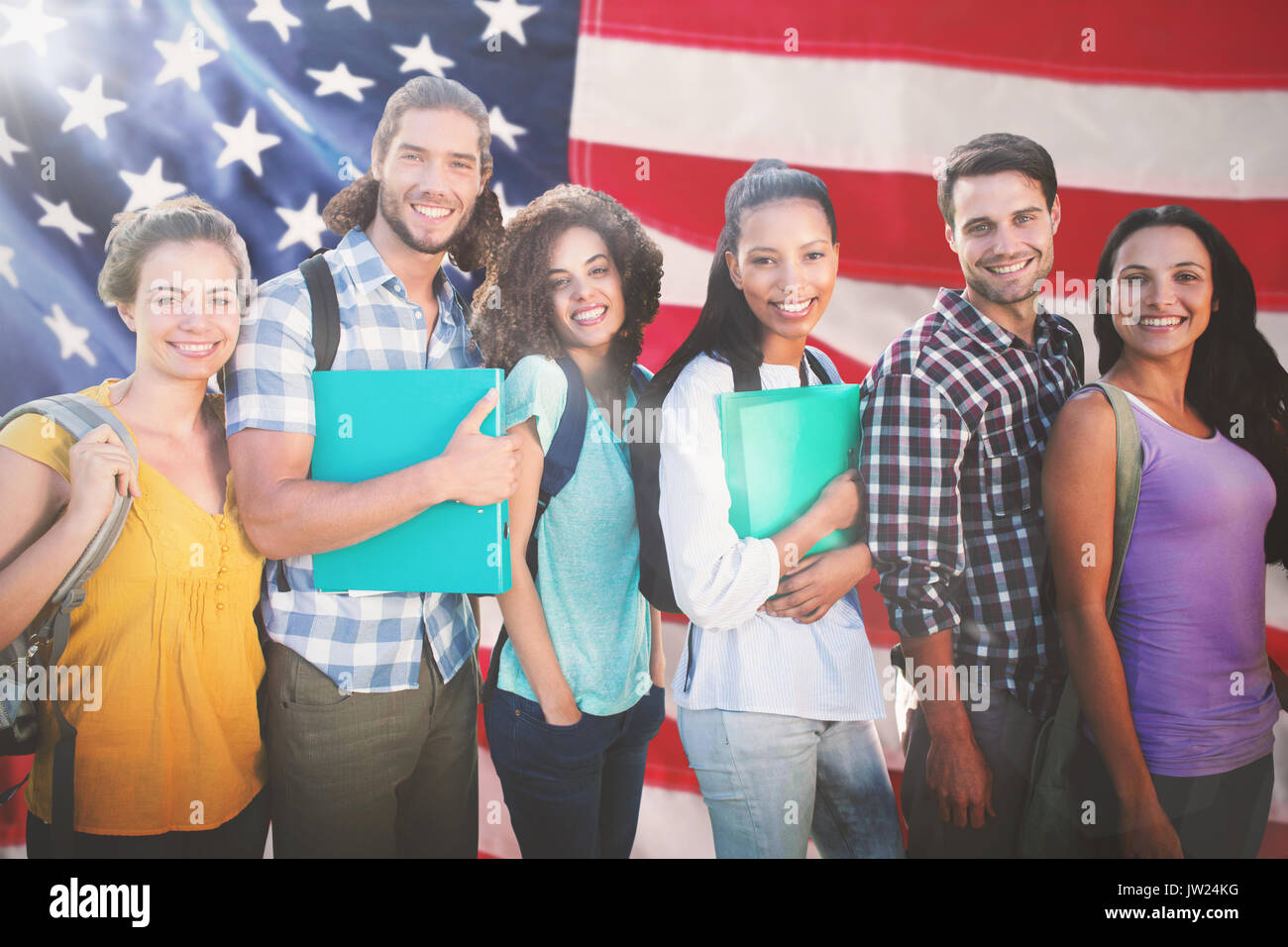 Smiling group of students standing in a row against close-up of an flag ...