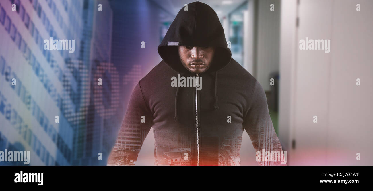 Male robber in black hoodie standing against composite image of binary ...