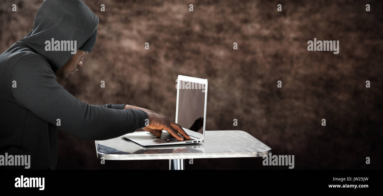 Male hacker using laptop on table against brown textured background ...