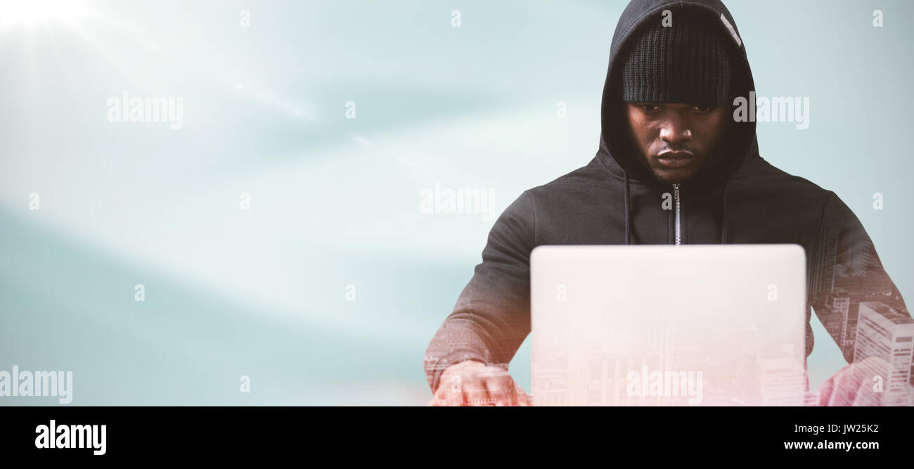 Serious male hacker with laptop against full frame shot of painted wall ...