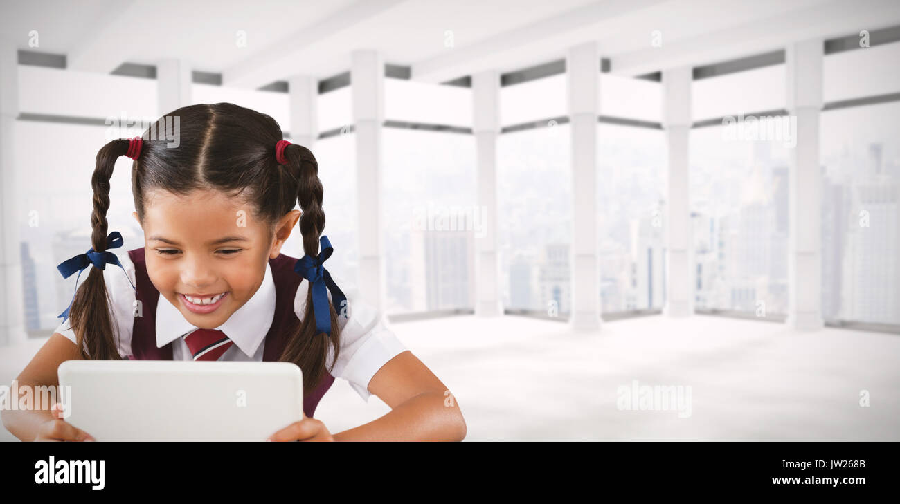 Schoolgirl using digital tablet at desk against windows overlooking ...