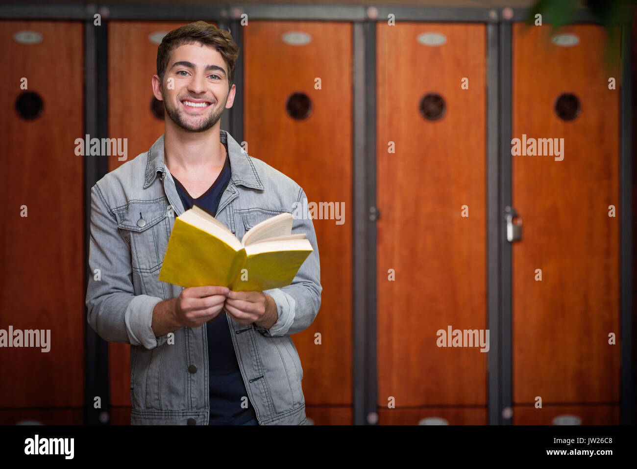 Student smiling at camera in library against close-up of brown lockers ...