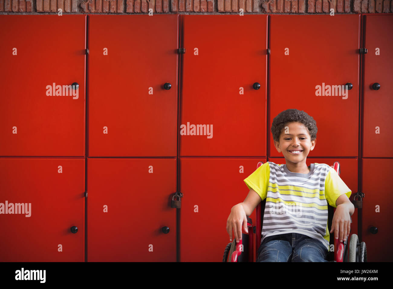 Cute disabled pupil smiling at camera in hall against close-up of ...
