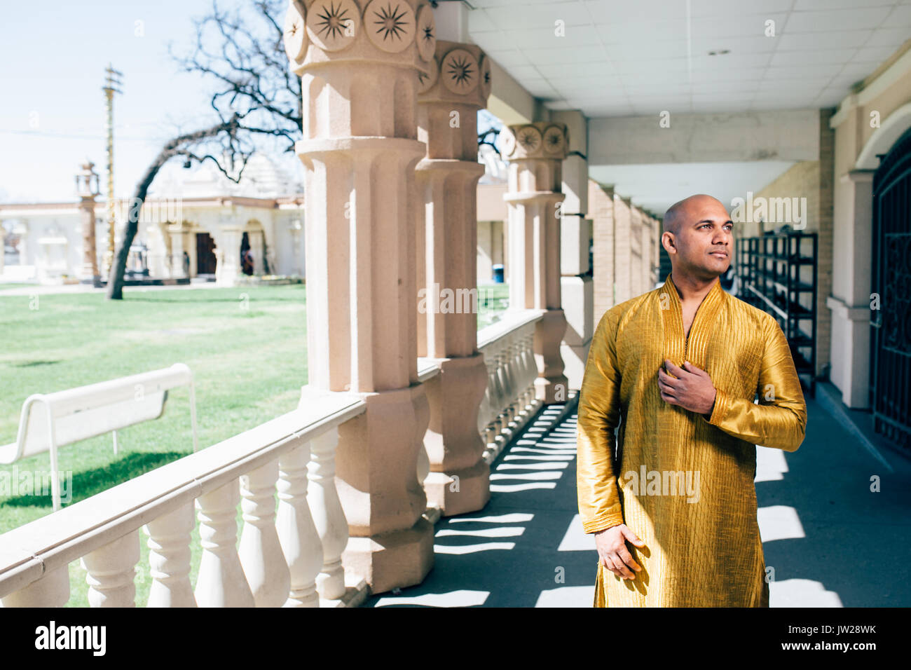 The handsome Indian man wears a gold kurta and posed at a temple Stock ...