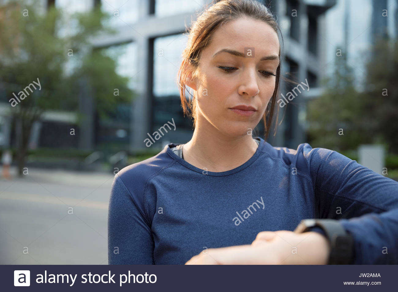 Female runner checking smart watch on urban street Stock Photo - Alamy