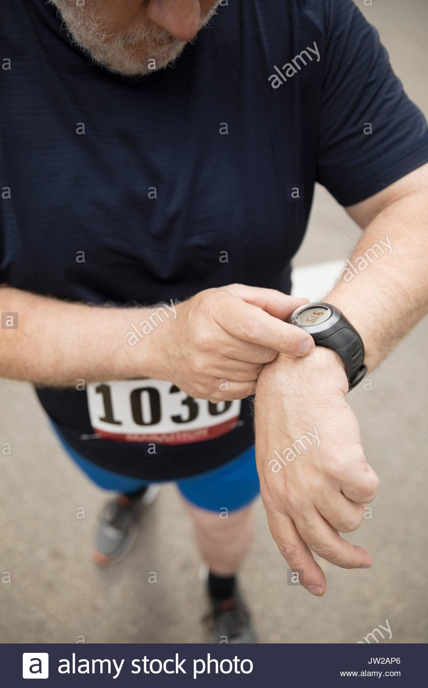 Close up male marathon runner checking smart watch Stock Photo - Alamy
