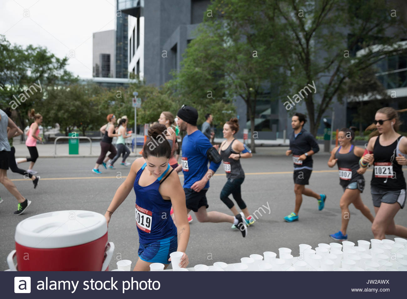 Female marathon runner grabbing a cup of water on urban street Stock ...