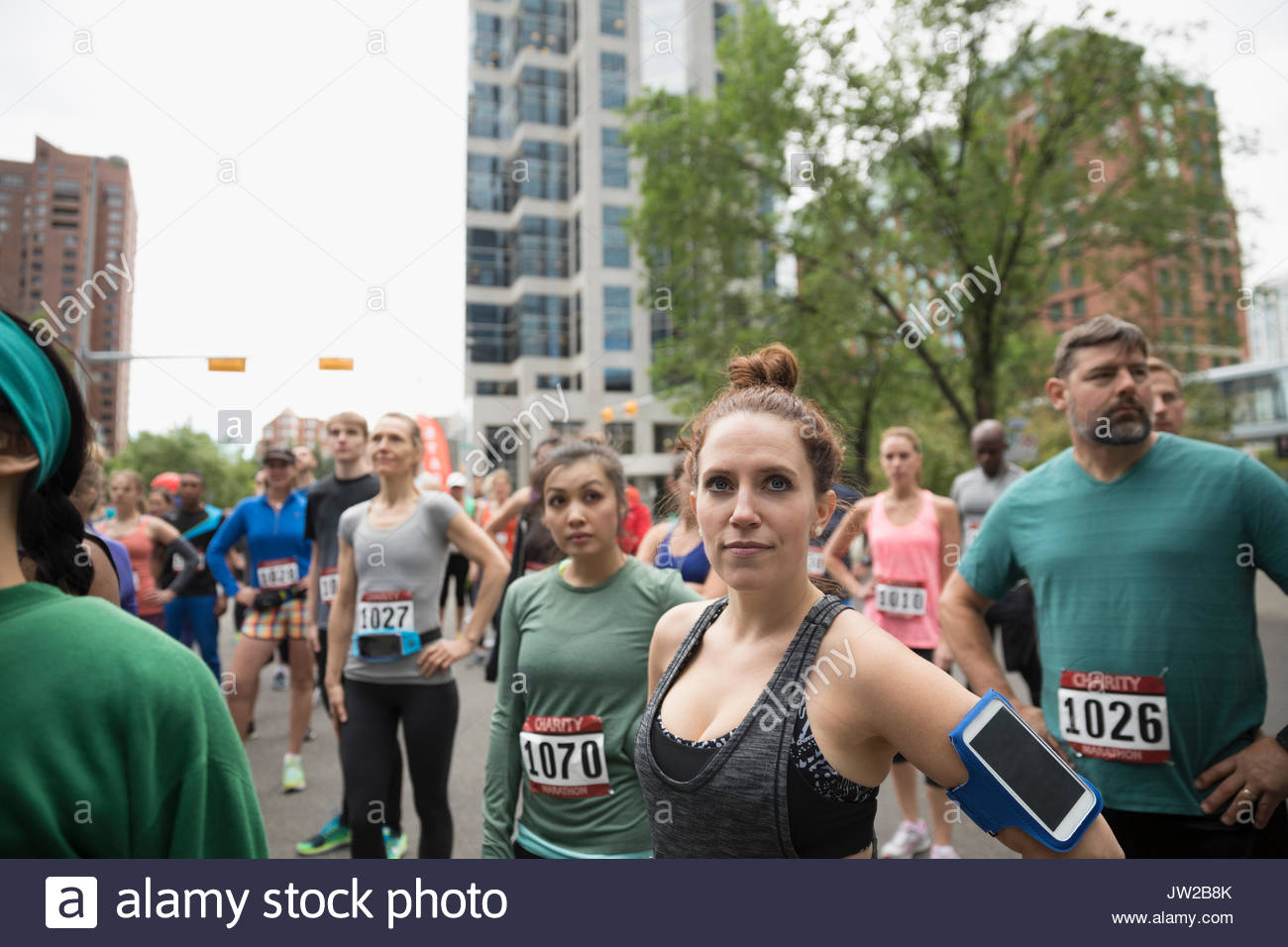 Portrait confident female marathon runner in crowd on urban street ...