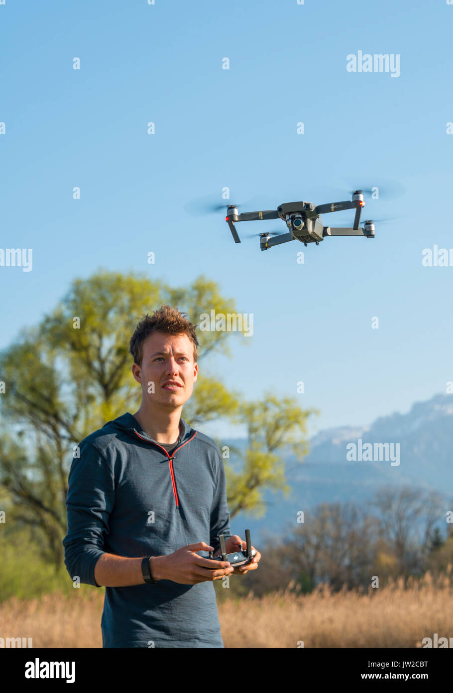 Young man controlling flying quadrocopter, remote controlled drone with ...