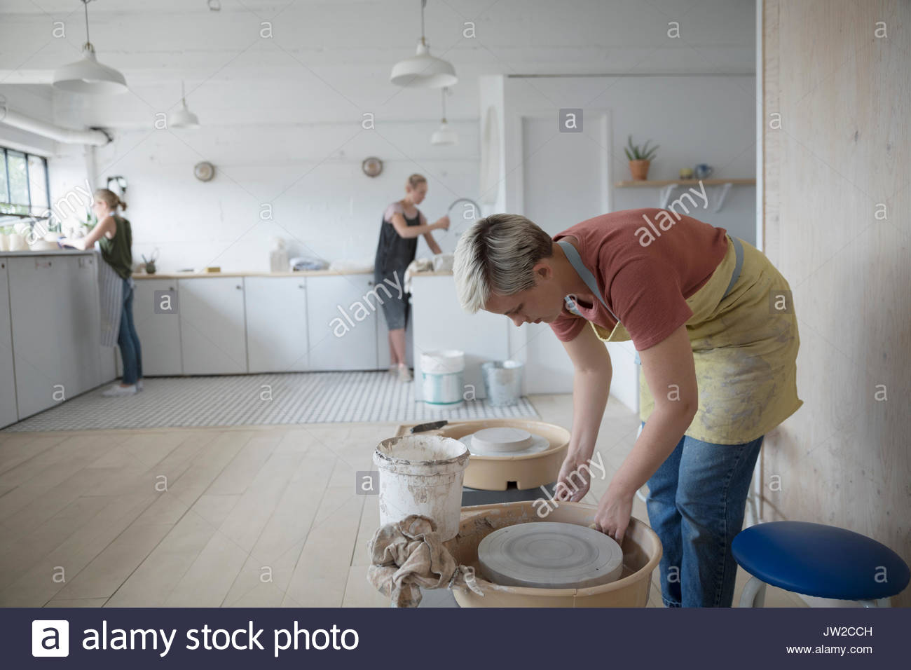 Female potter bending over pottery wheel in art studio Stock Photo - Alamy