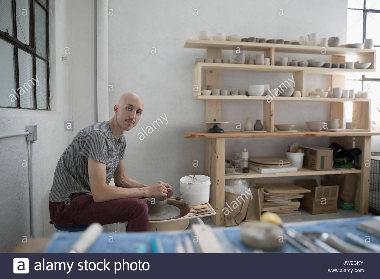 Portrait confident male potter using pottery wheel in art studio Stock ...