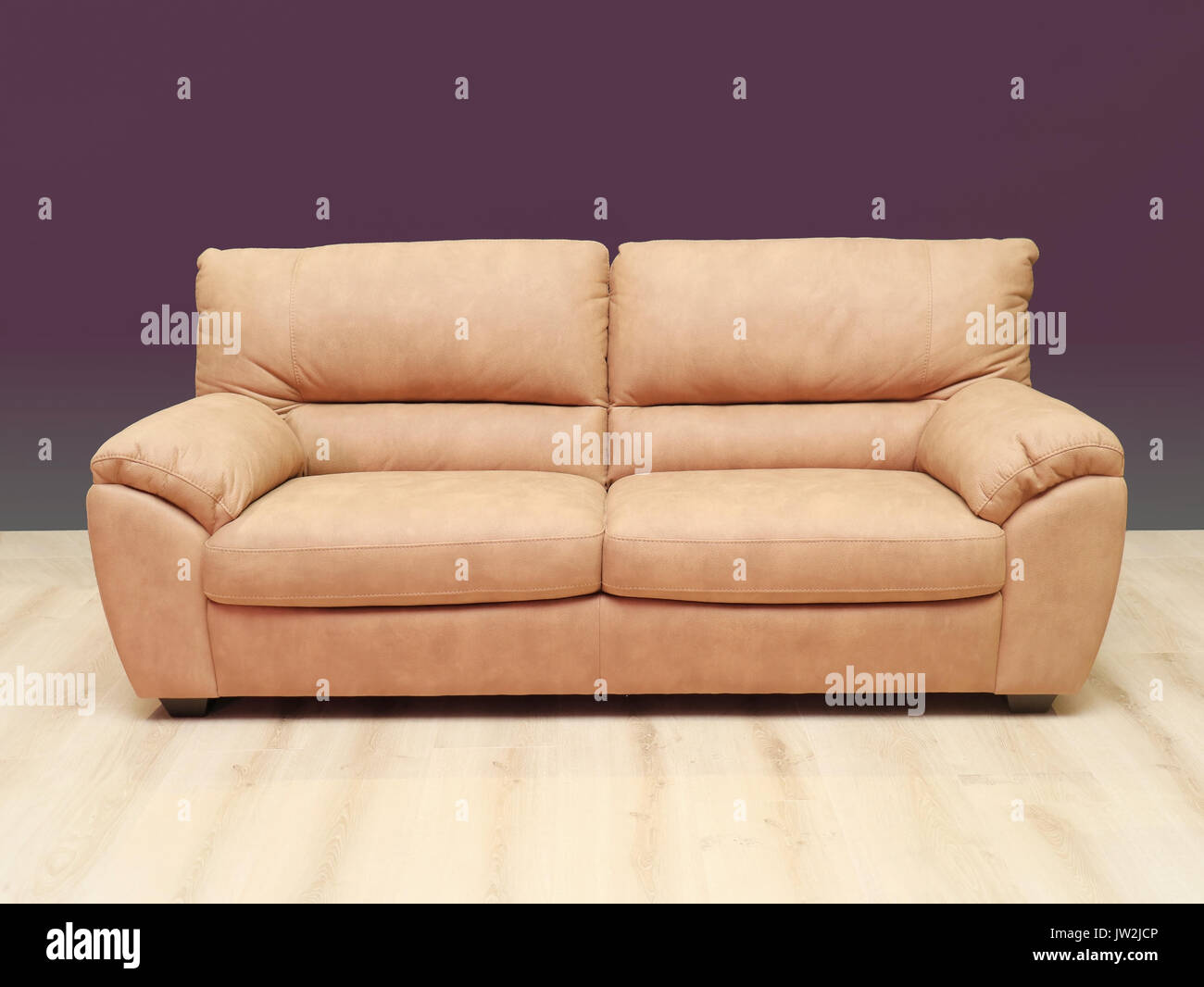 Beige leather sofa inside interior with purple wall and wooden floor ...