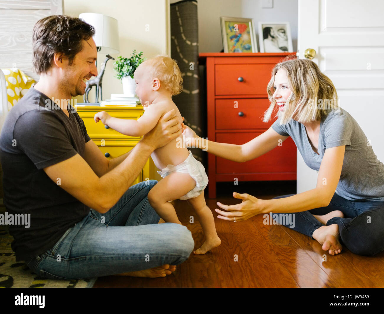 Baby boy (12-17 months) taking first steps with parents at home Stock ...