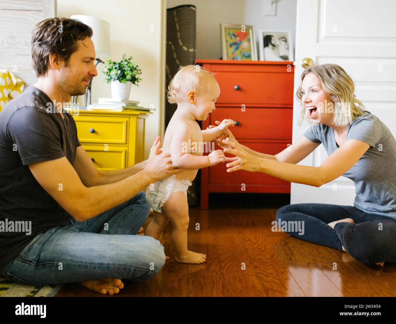 Baby boy (12-17 months) taking first steps with parents at home Stock ...