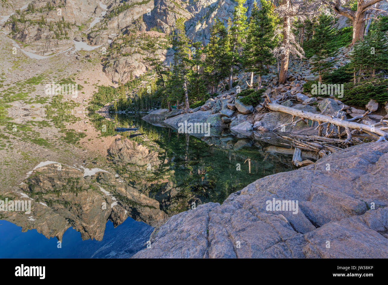 Snow below Flattop Mountain reflected in perfectly still Emerald Lake ...