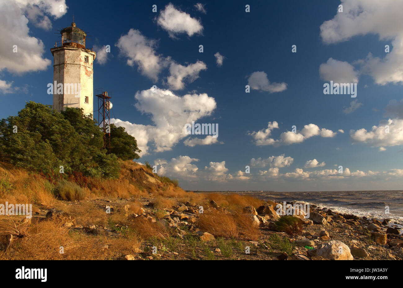 Old vintage beacon (lighthouse) at the sea cost with stones and dry ...