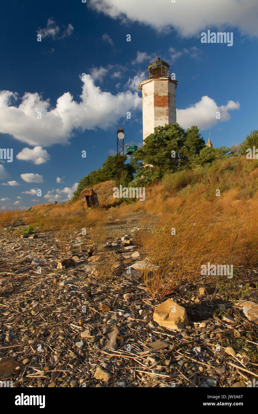 Old vintage beacon (lighthouse) at the sea cost with stones and dry ...