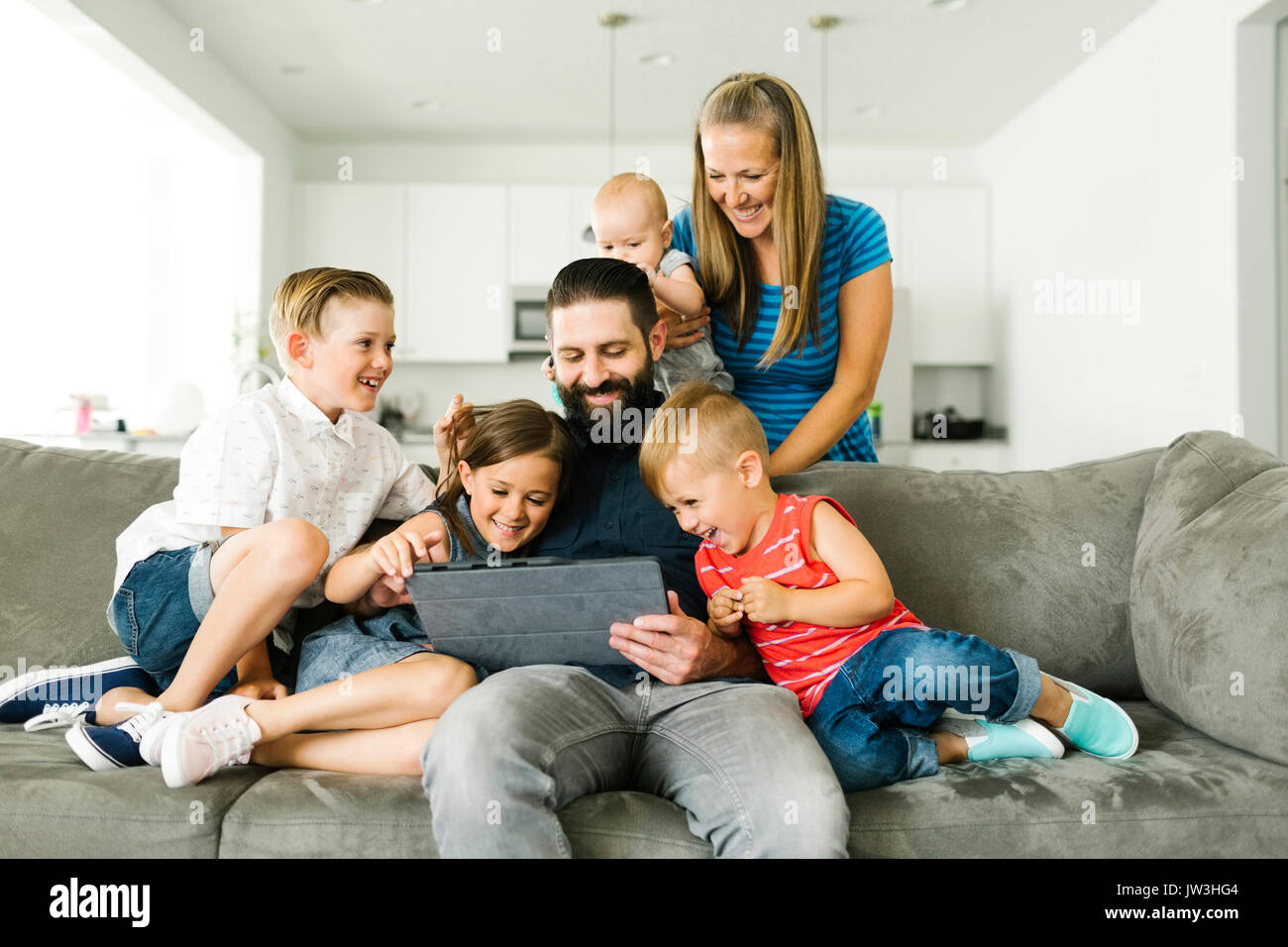Family with four children (6-11 months, 2-3, 6-7) using digital tablet ...