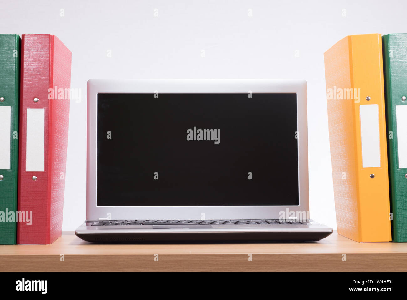 Multicoloured office document folders and an open laptop computer on a ...