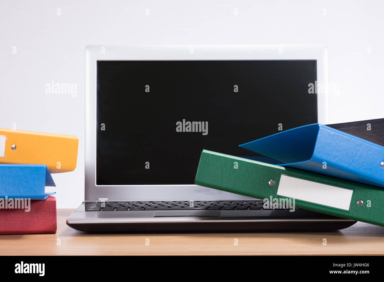 A messy office desk with open computer laptop, document folders and a ...